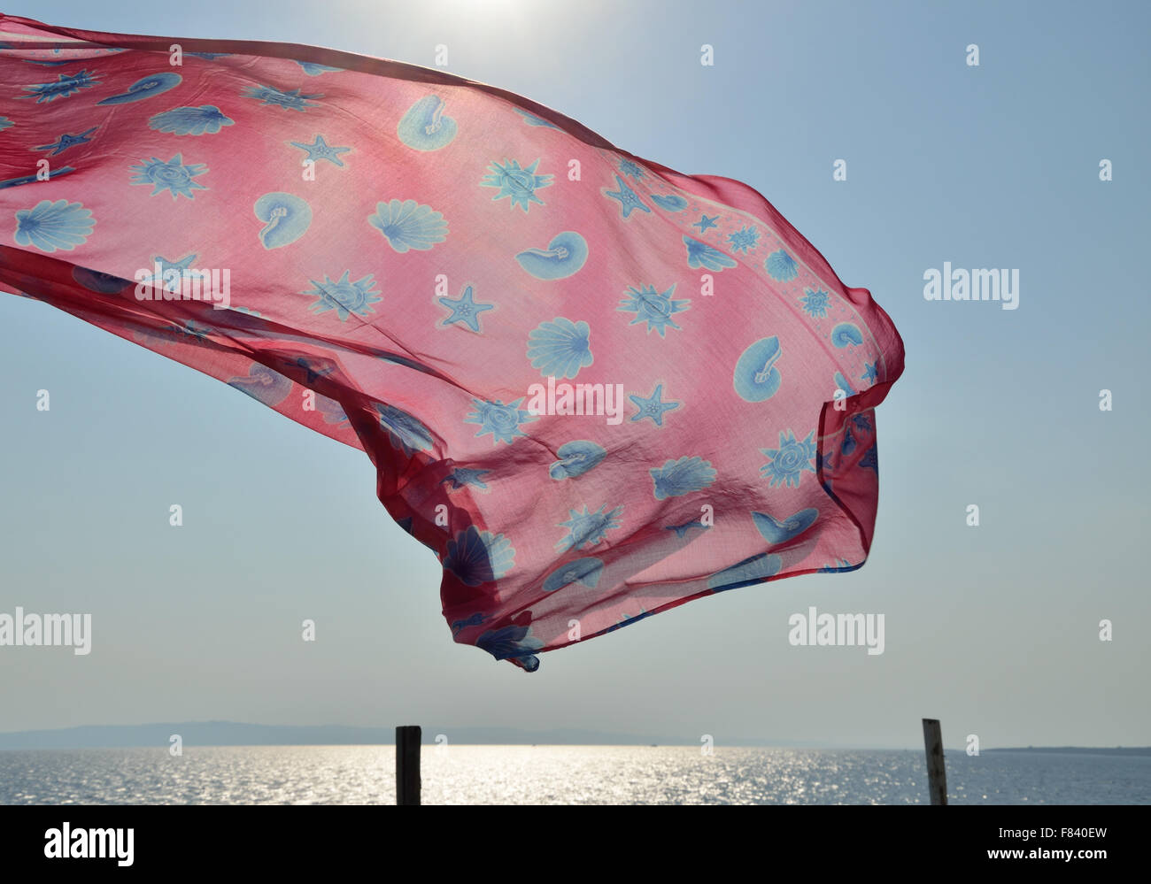 Pink beach scarf flying on summer breeze in sunset with sea horizon in ...