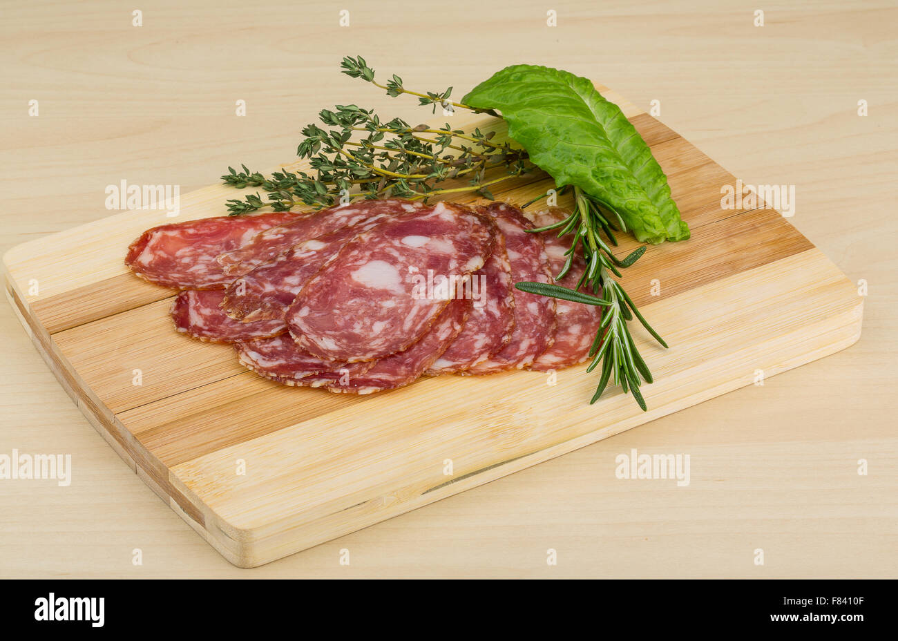 Sliced Salami with herbs on the wooden bckground Stock Photo - Alamy