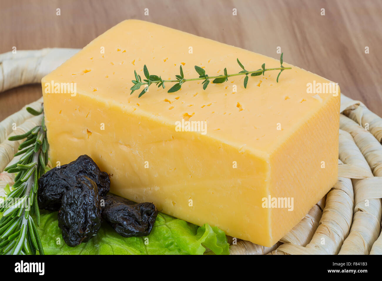 Brick of yellow cheese with thyme and plum Stock Photo - Alamy