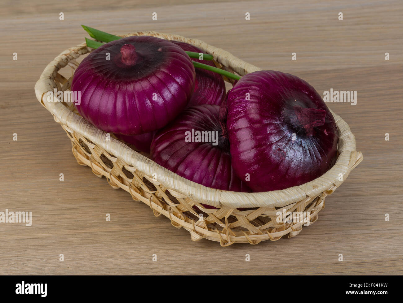 Violet onion in the basket with green Stock Photo - Alamy
