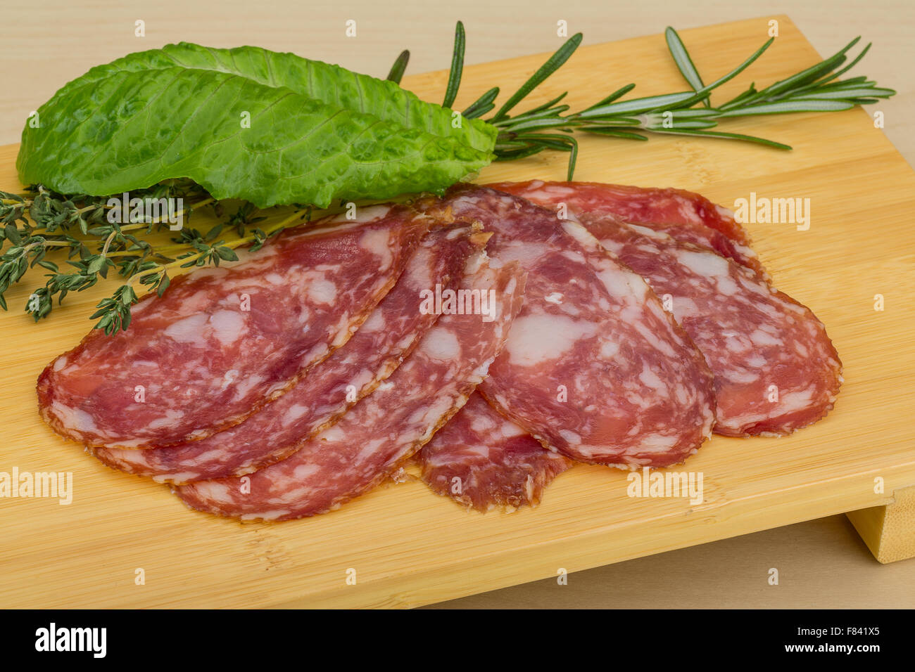 Sliced Salami with herbs on the wooden bckground Stock Photo - Alamy