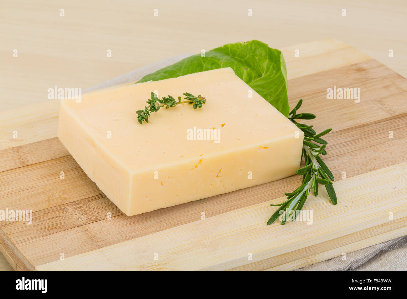 Yellow cheese brick with rosemary and thyme Stock Photo - Alamy
