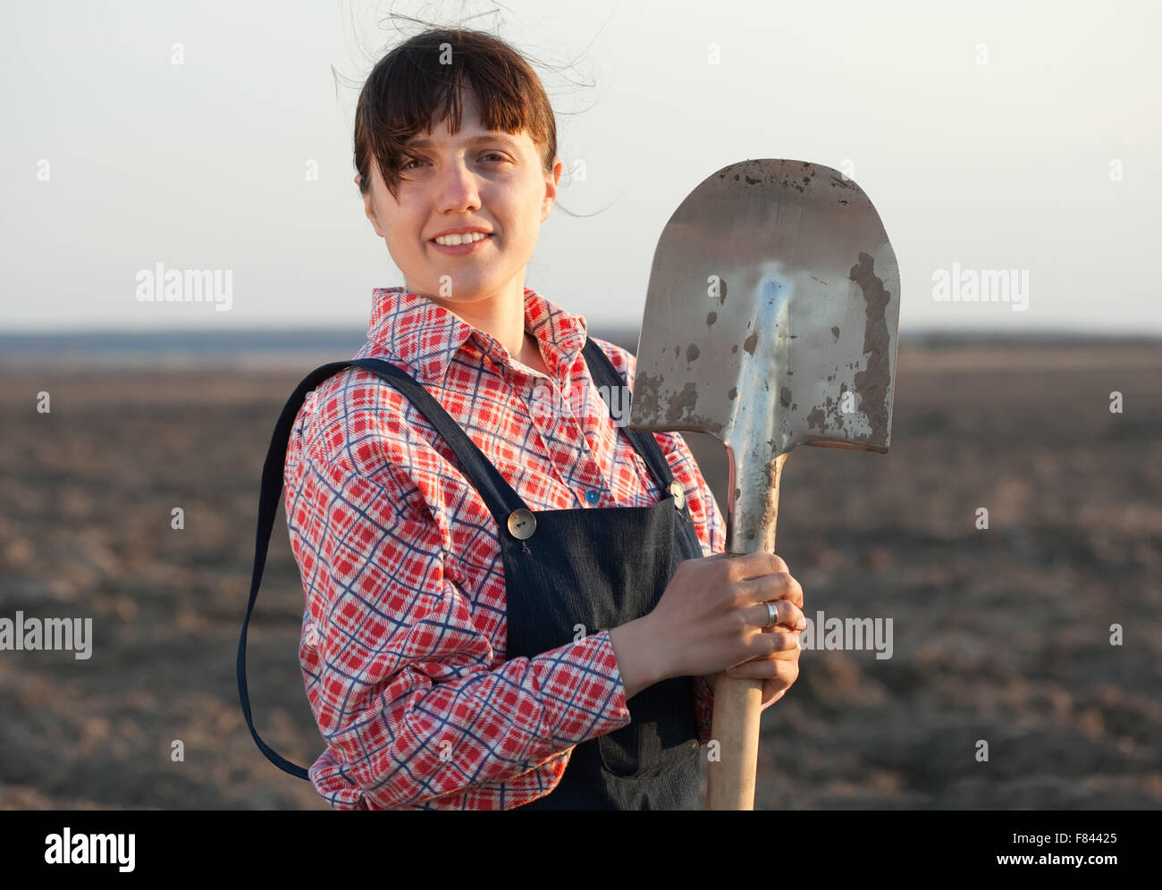 Happy female farmer with shovel in field Stock Photo - Alamy