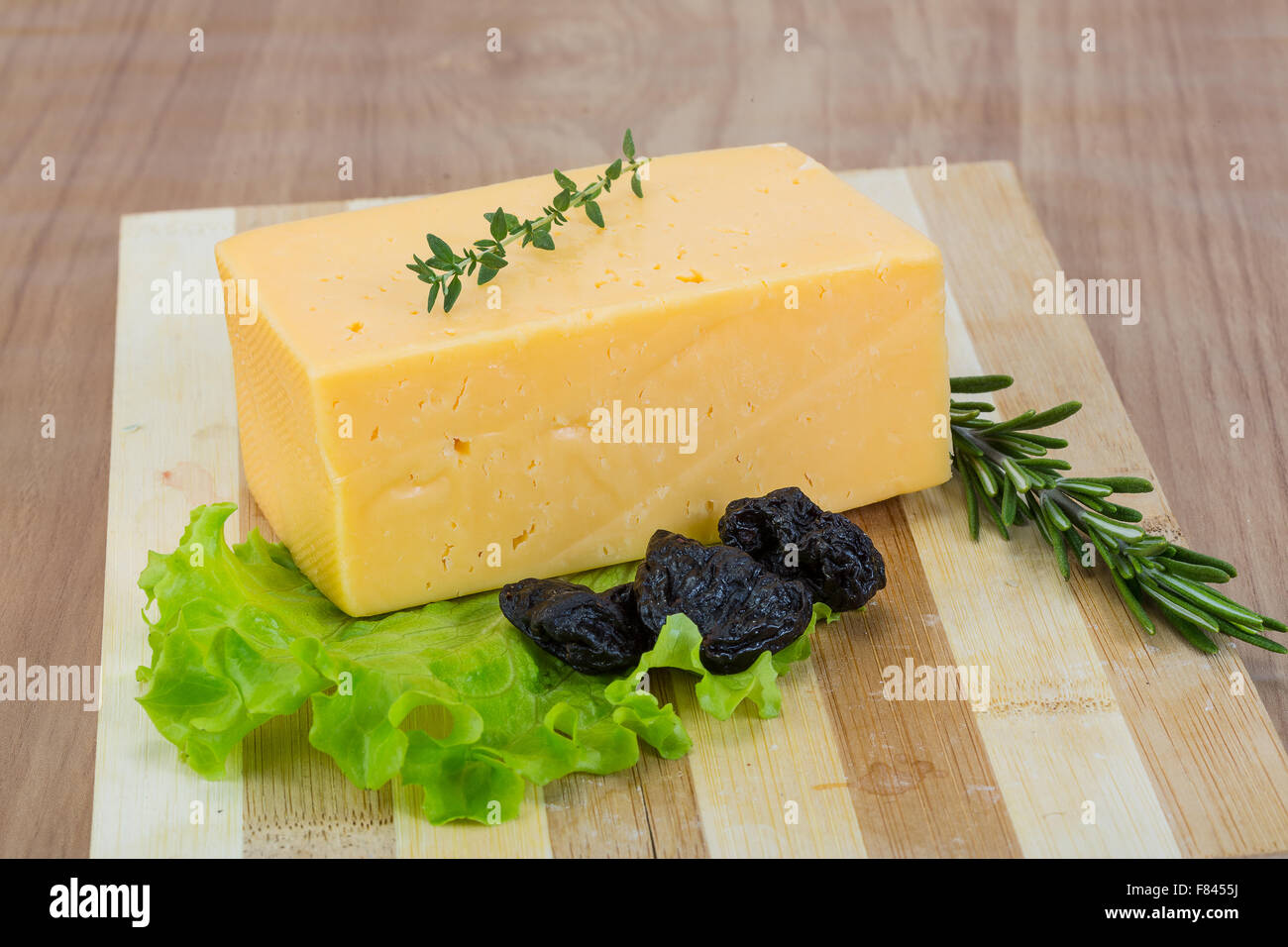 Brick of yellow cheese with thyme and plum Stock Photo - Alamy