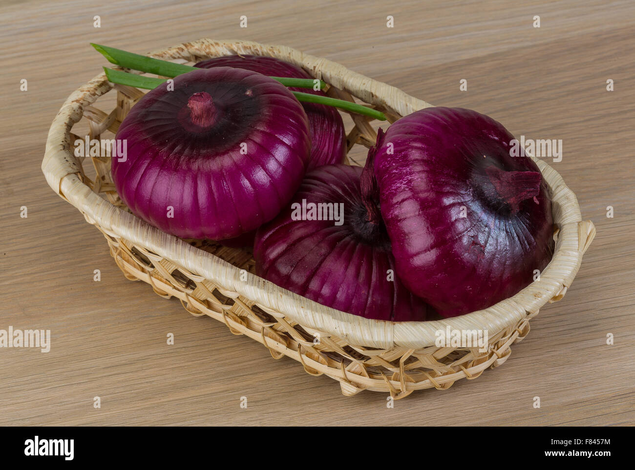 Violet onion in the basket with green Stock Photo - Alamy