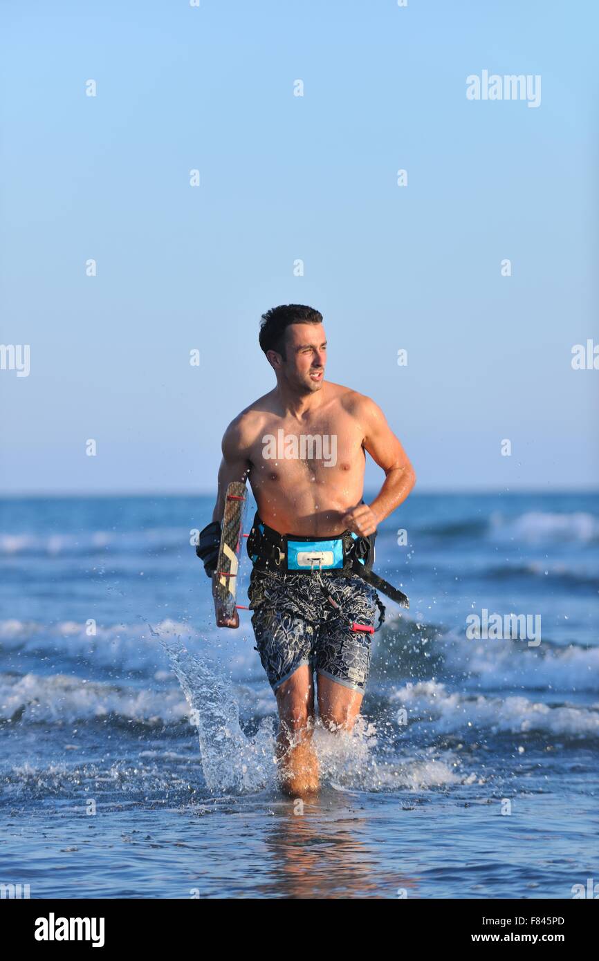 Portrait of a strong young surf man at beach on sunset in a ...