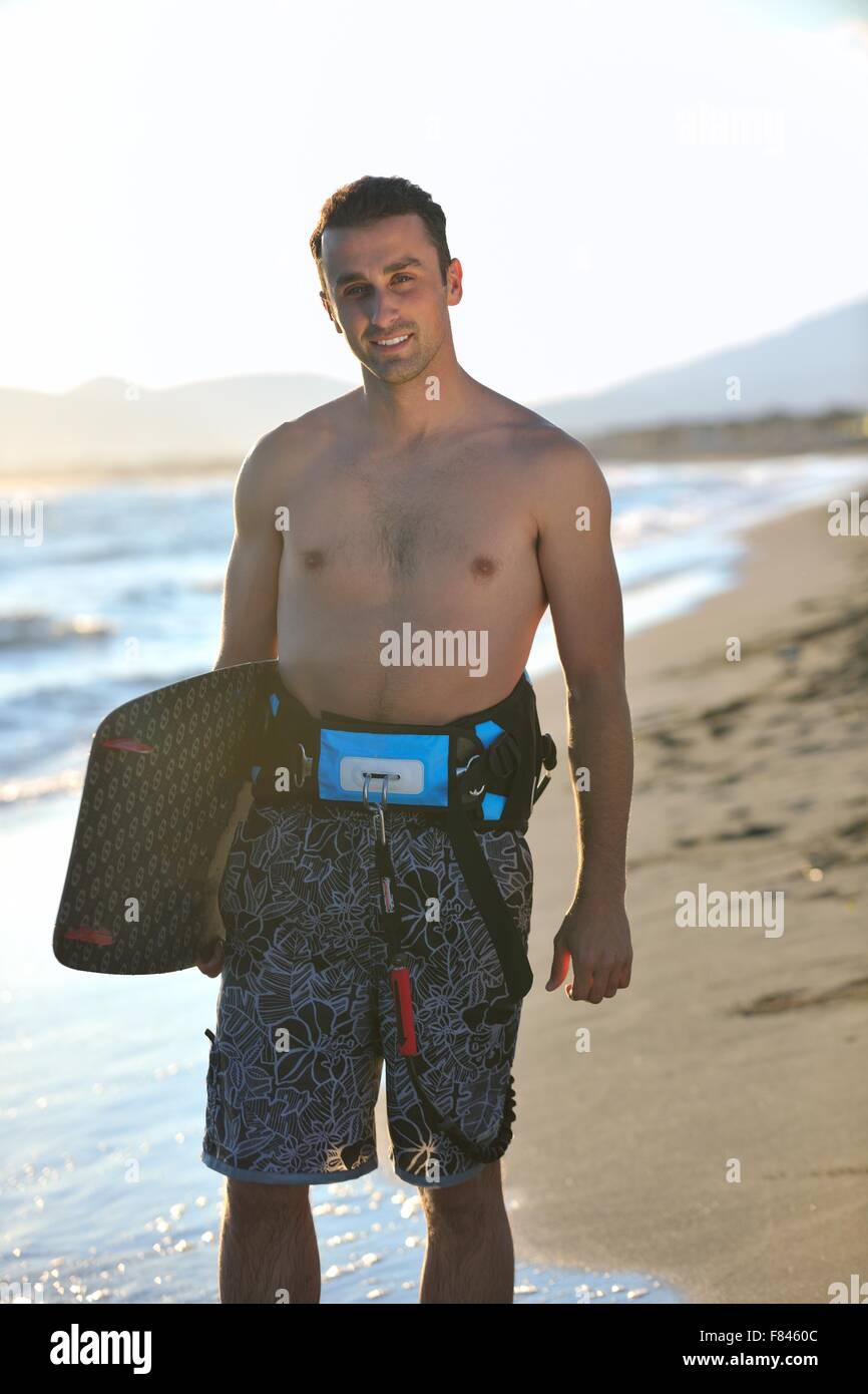 Portrait of a strong young surf man at beach on sunset in a ...