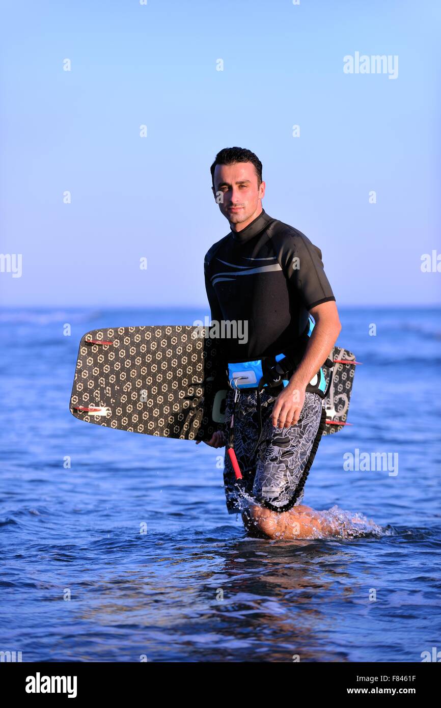 Portrait of a strong young surf man at beach on sunset in a ...