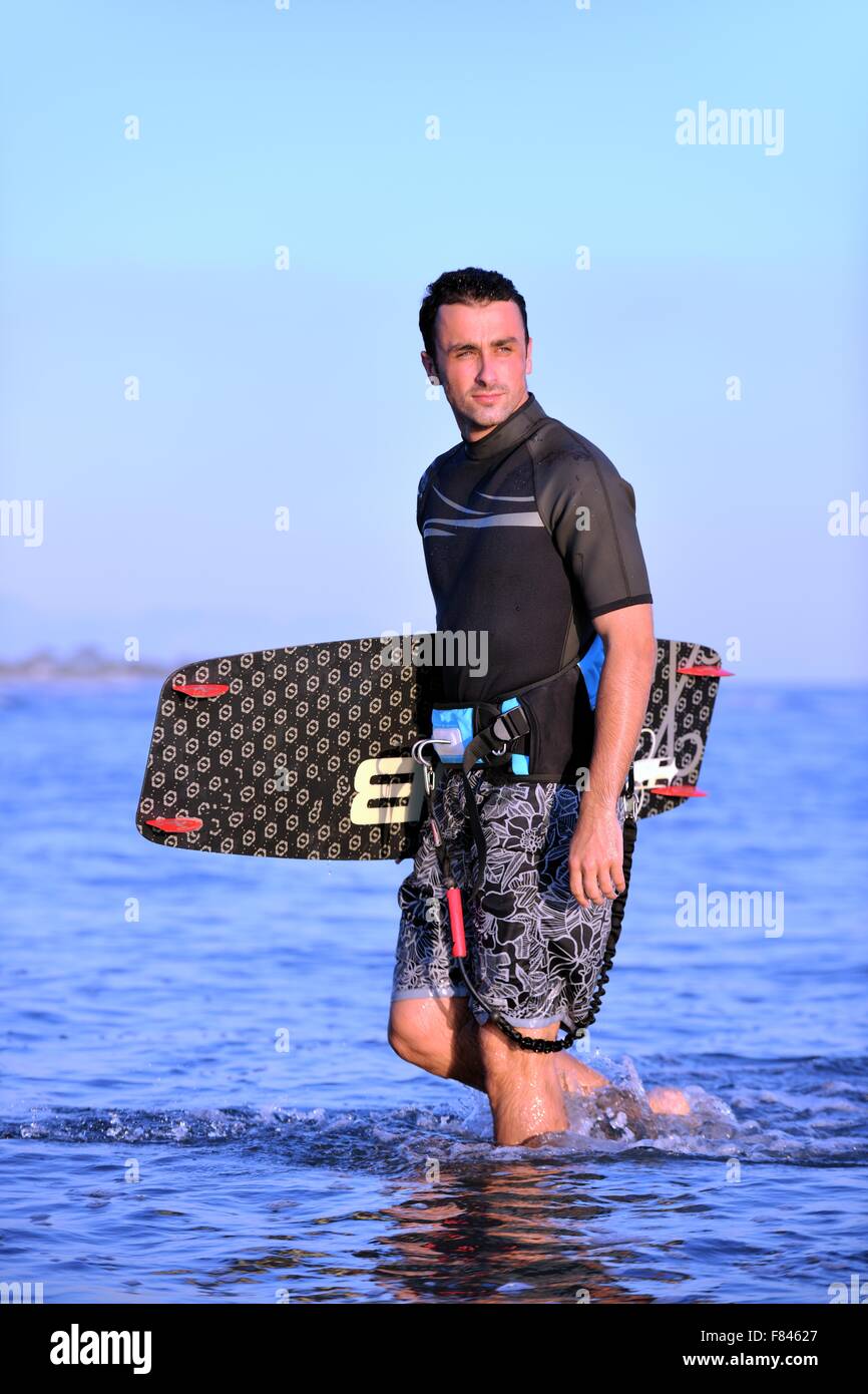 Portrait of a strong young surf man at beach on sunset in a ...