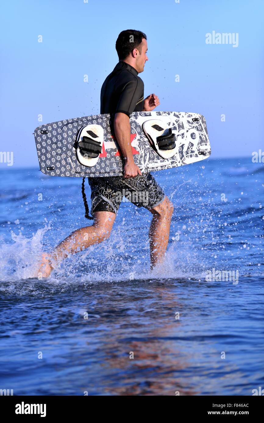 Portrait of a strong young surf man at beach on sunset in a ...