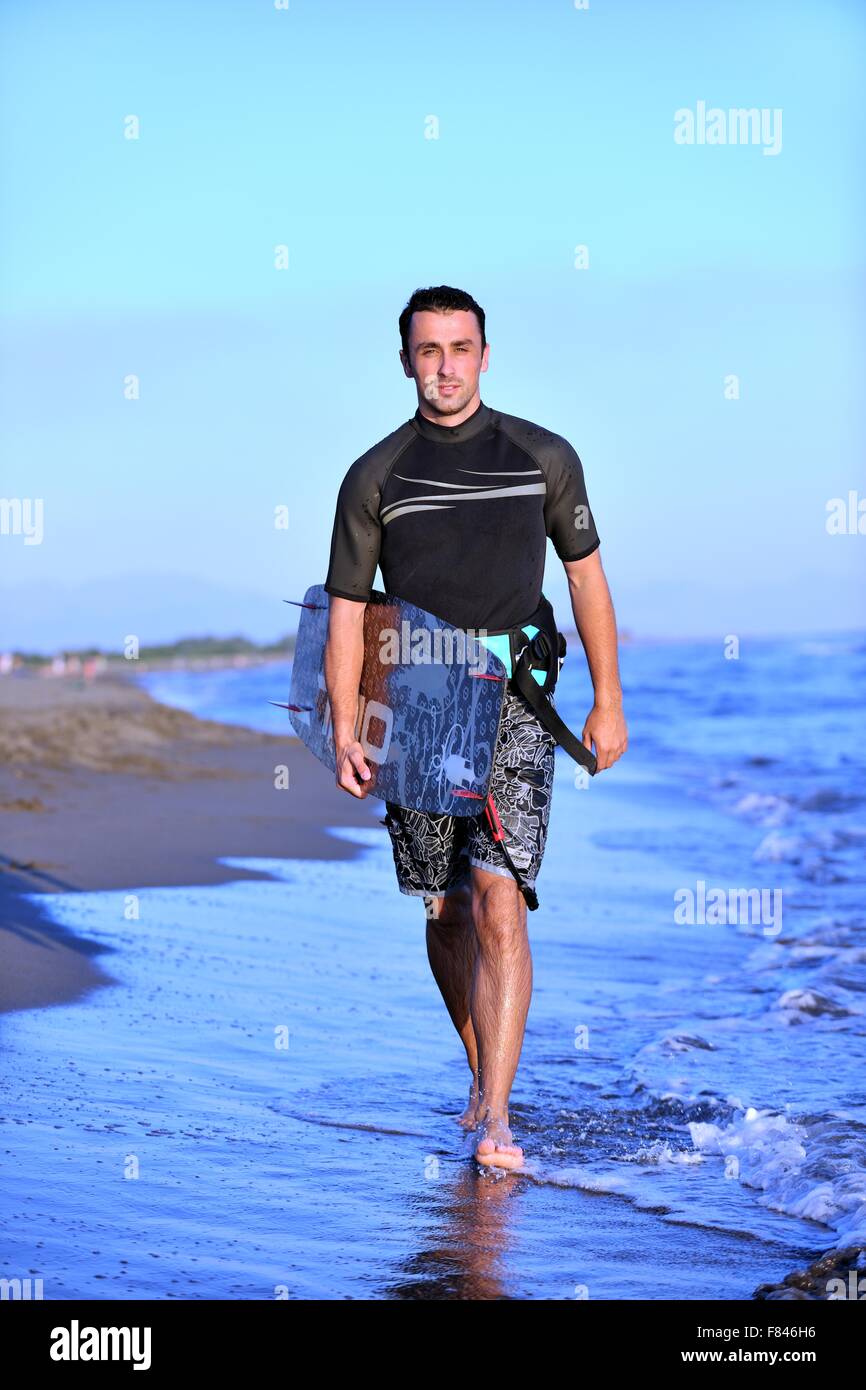 Portrait of a strong young surf man at beach on sunset in a ...
