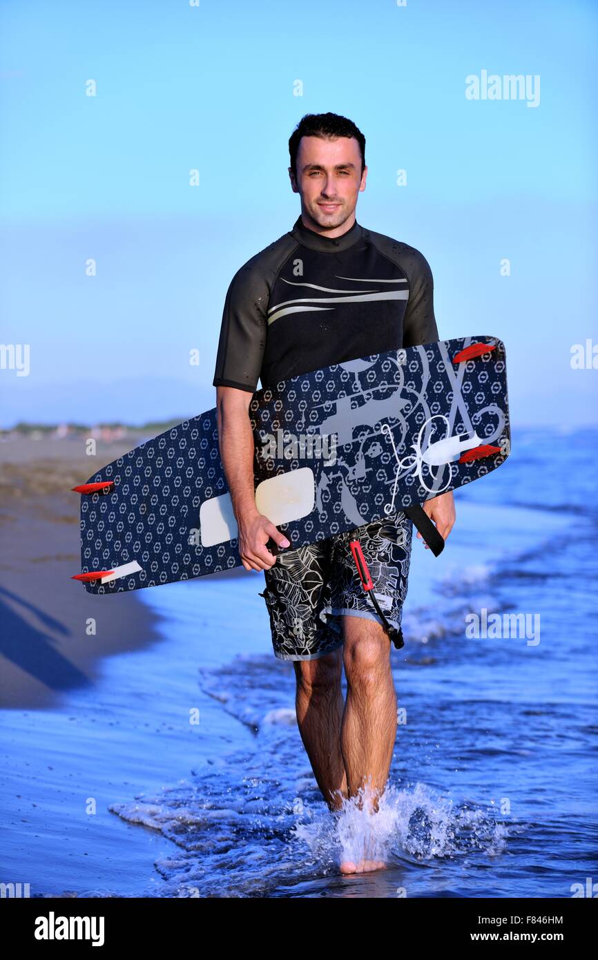 Portrait of a strong young surf man at beach on sunset in a ...