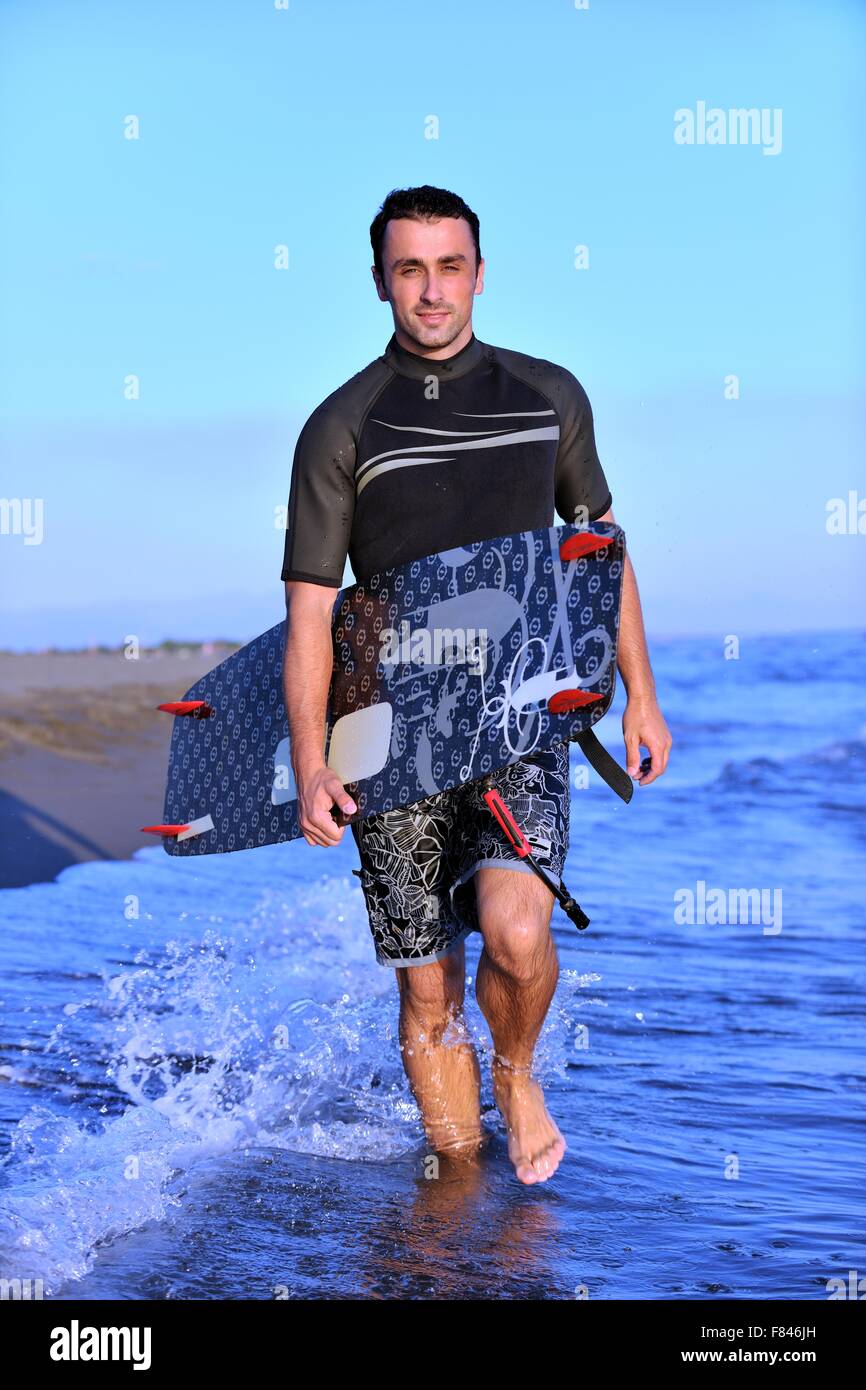 Portrait of a strong young surf man at beach on sunset in a ...