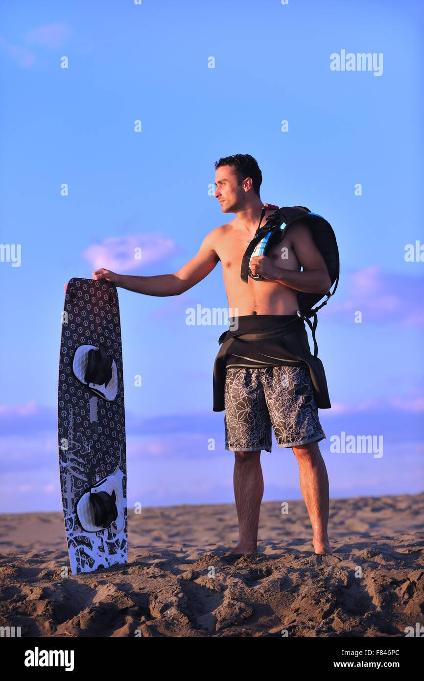 Portrait of a strong young surf man at beach on sunset in a ...