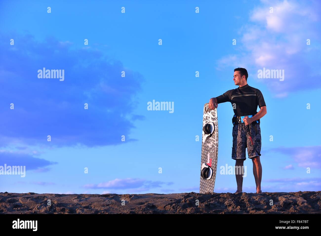 Portrait of a strong young surf man at beach on sunset in a ...