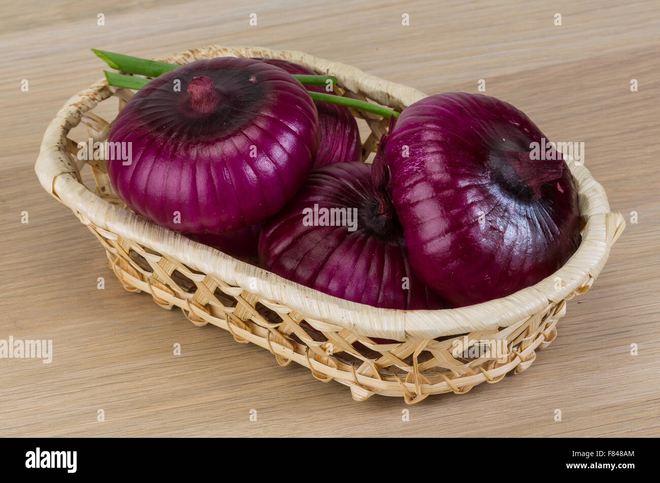Violet onion in the basket with green Stock Photo - Alamy
