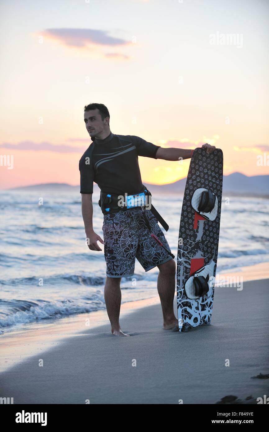 Portrait of a strong young surf man at beach on sunset in a ...