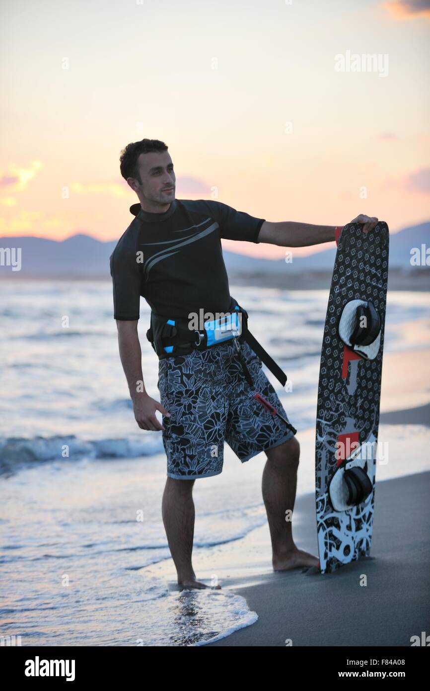 Portrait of a strong young surf man at beach on sunset in a ...