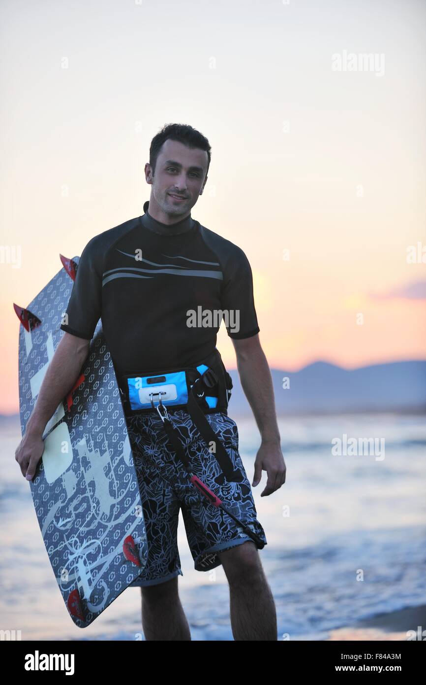 Portrait of a strong young surf man at beach on sunset in a ...