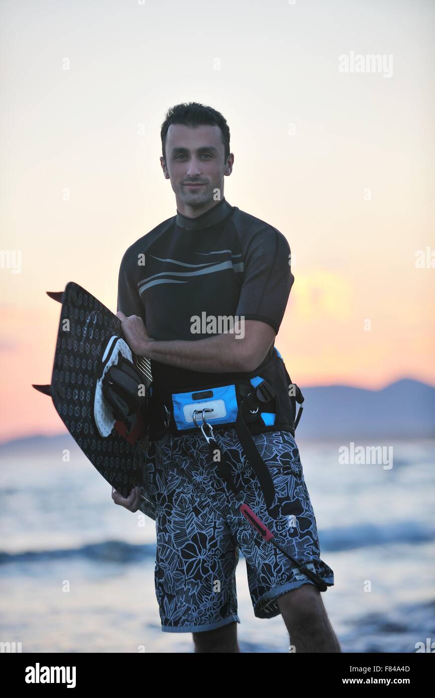Portrait of a strong young surf man at beach on sunset in a ...