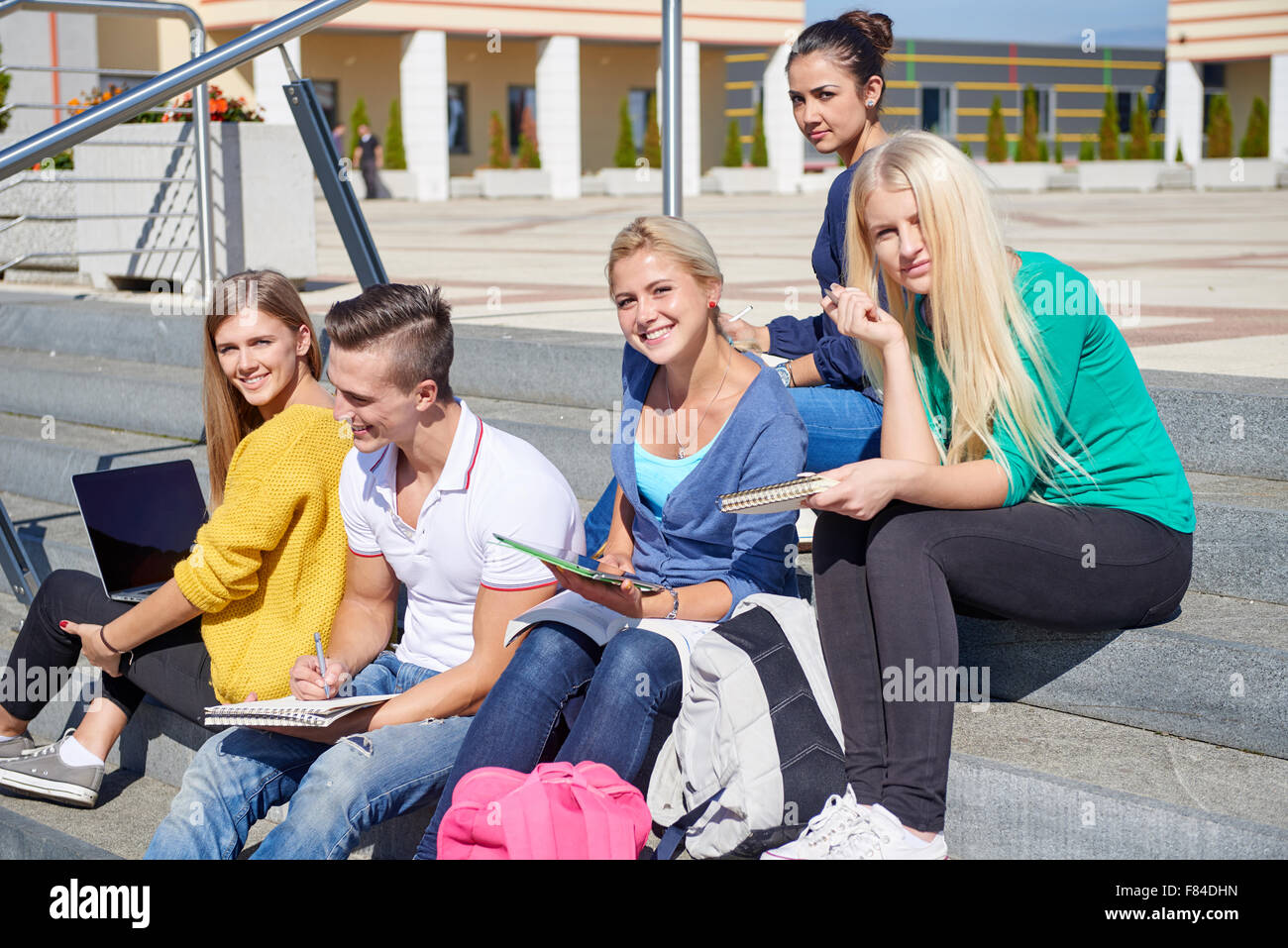 Group portrait of happy students outside sitting on steps have fun ...