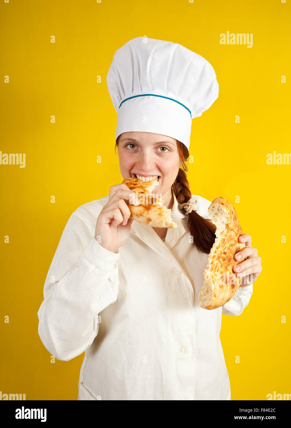 female baker is eating fresh loaf over yellow Stock Photo - Alamy