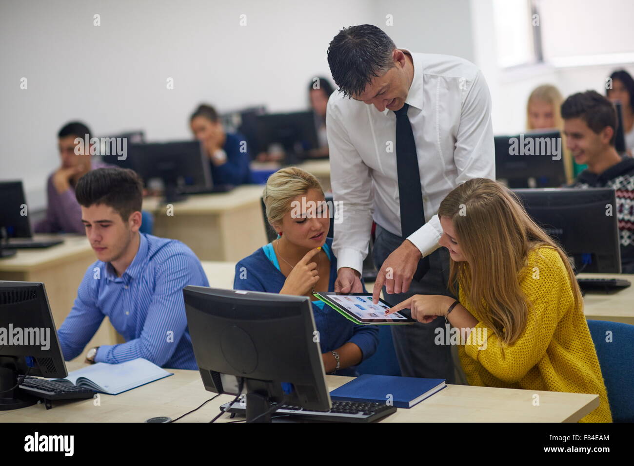 group of students with teacher in computer lab classrom learrning ...