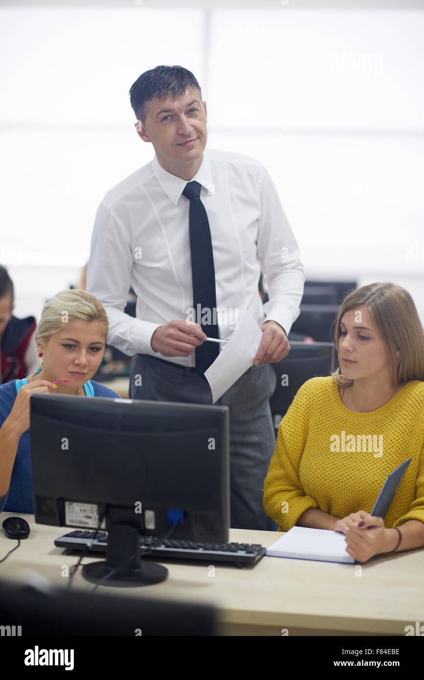 group of students with teacher in computer lab classrom learrning ...