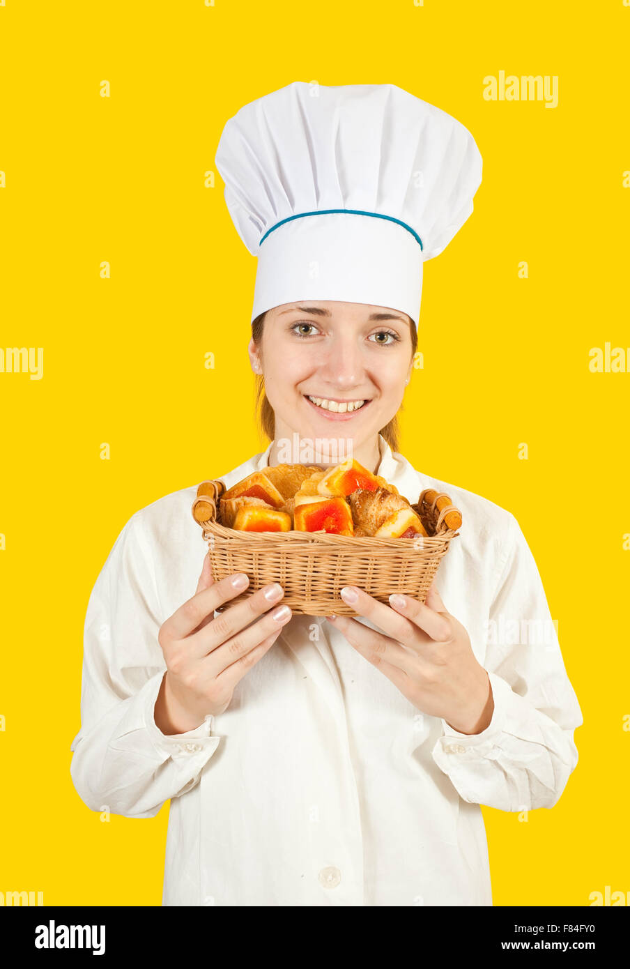 Attractive cook woman in toque with pastry over yellow background Stock ...
