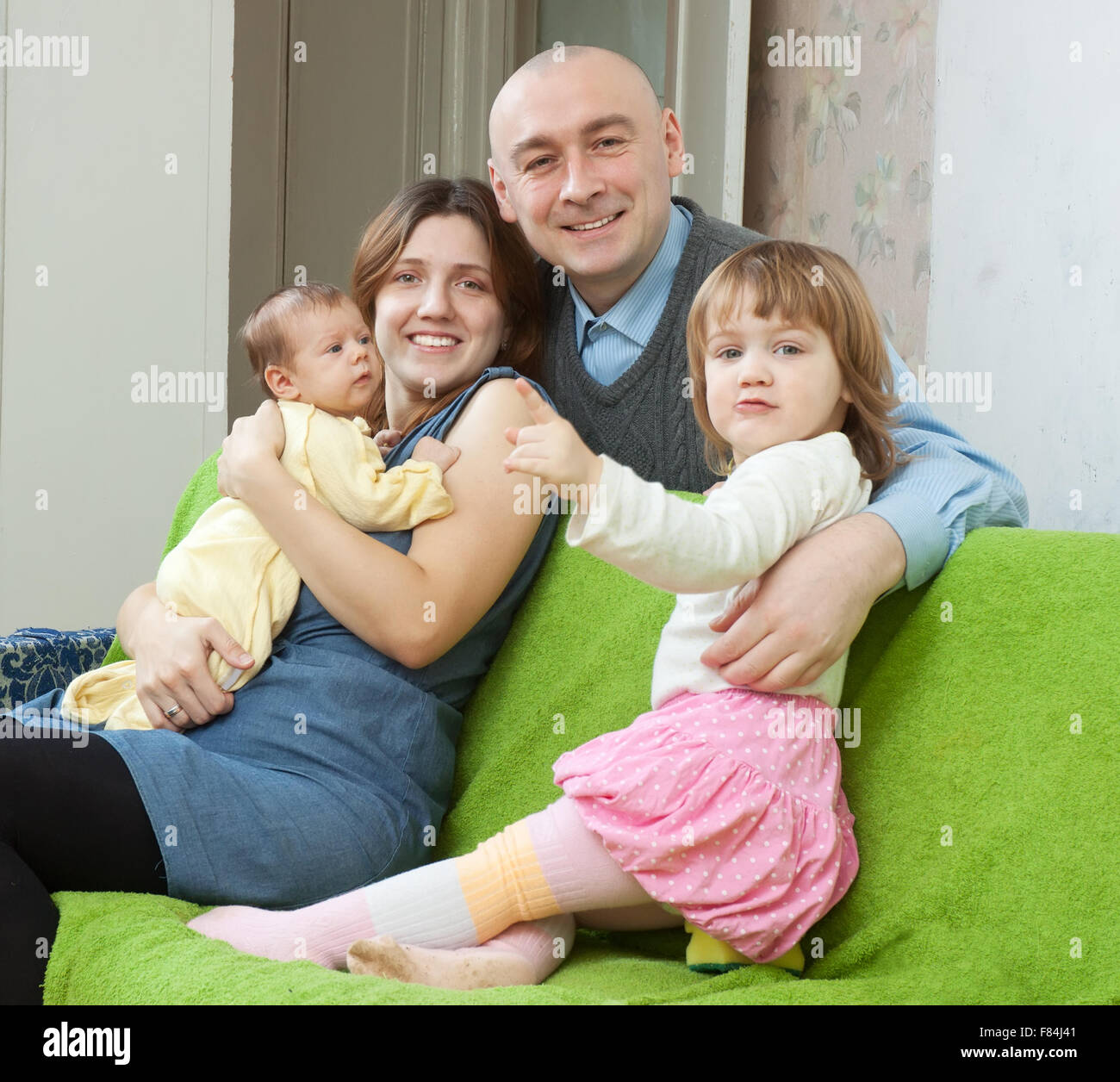 Smiling parents with their two kids at home interior Stock Photo - Alamy