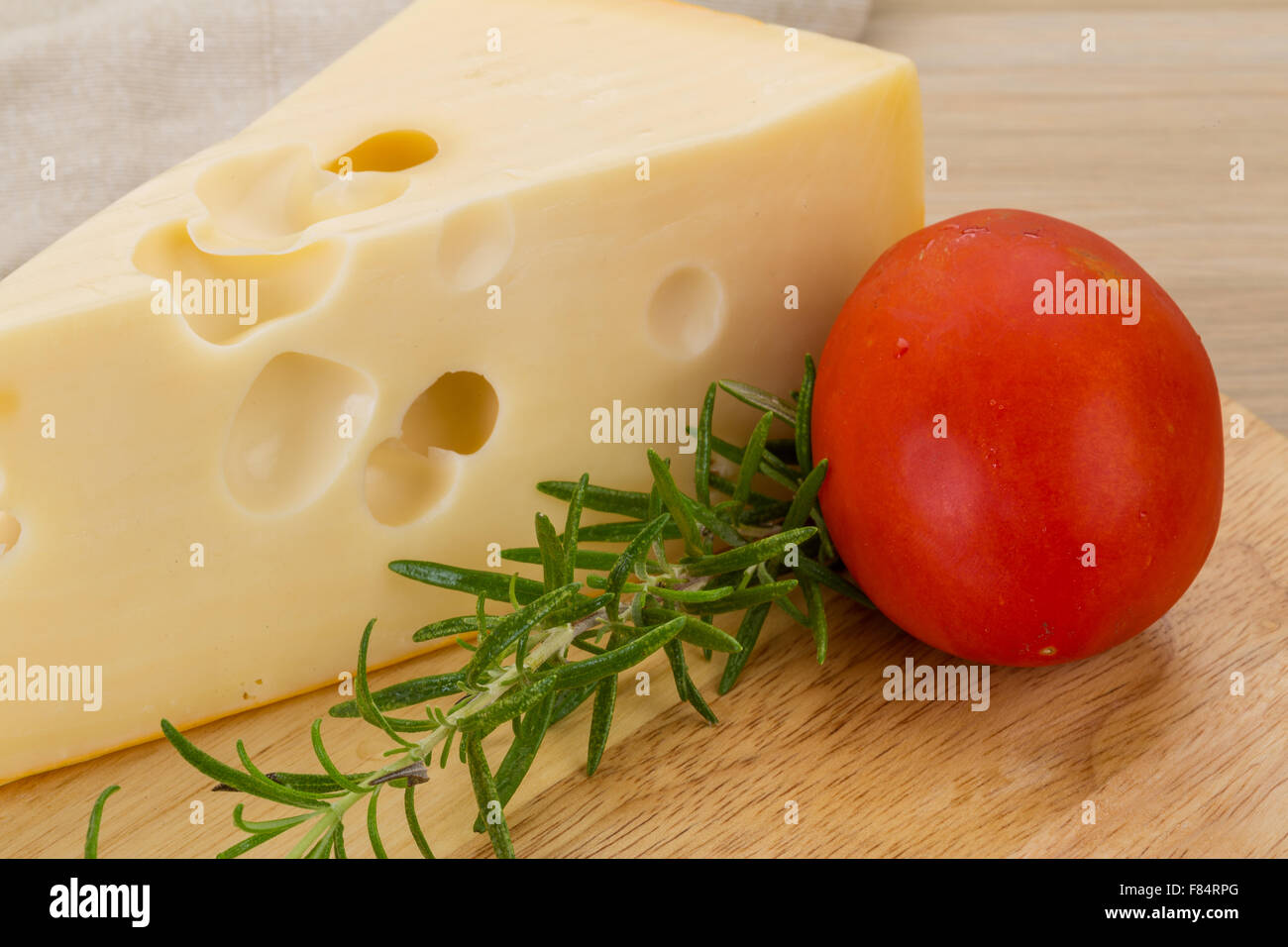 Yellow Cheese maasdam - on the board with herbs Stock Photo - Alamy