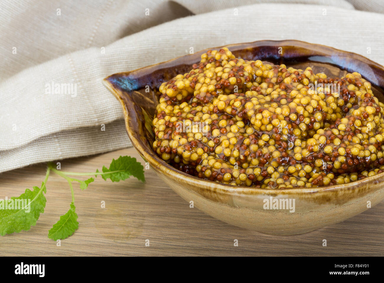 French mustard with fresh leaves on wooden background Stock Photo - Alamy