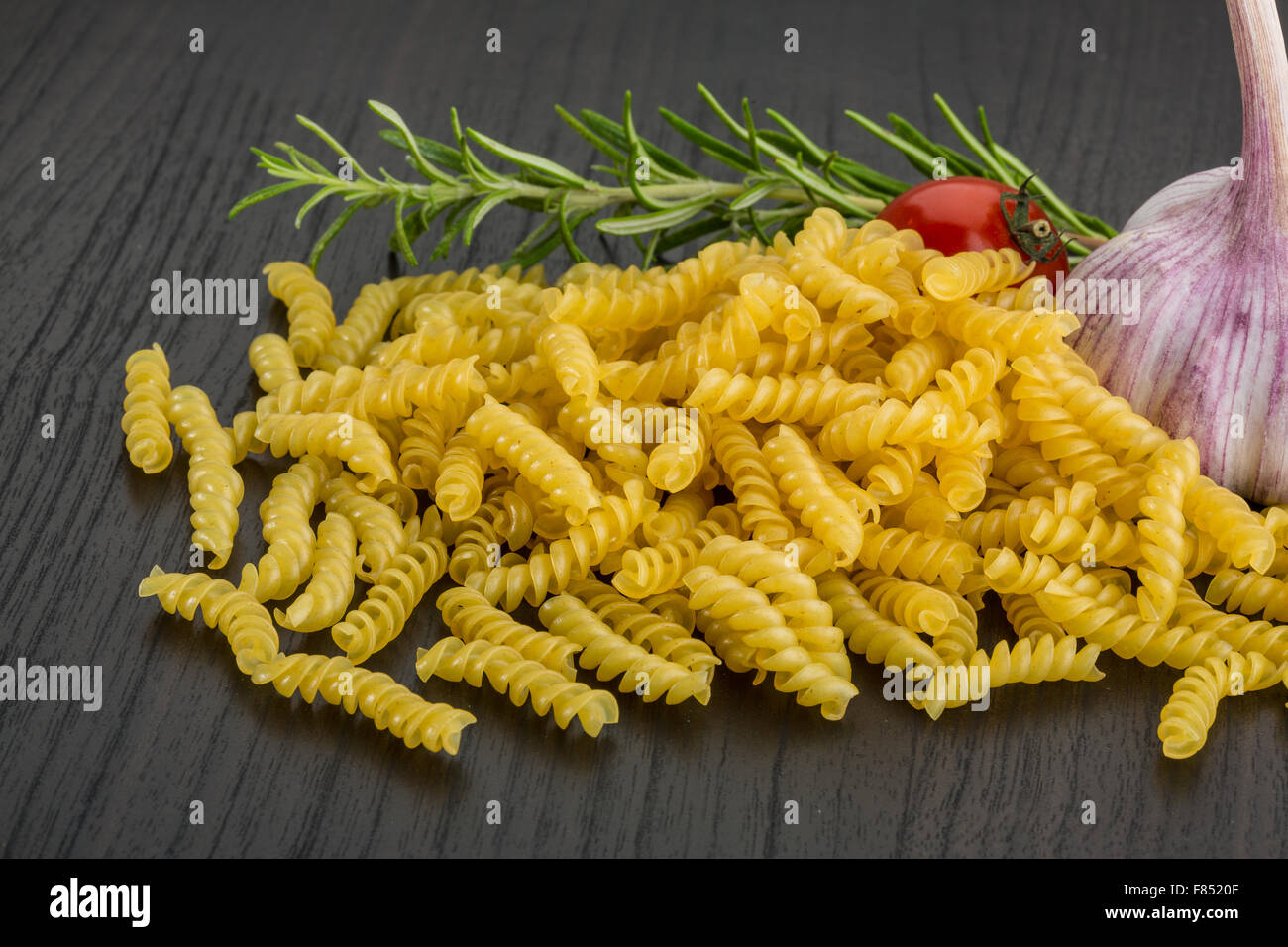 Raw fusilli with rosemary and tomato Stock Photo - Alamy