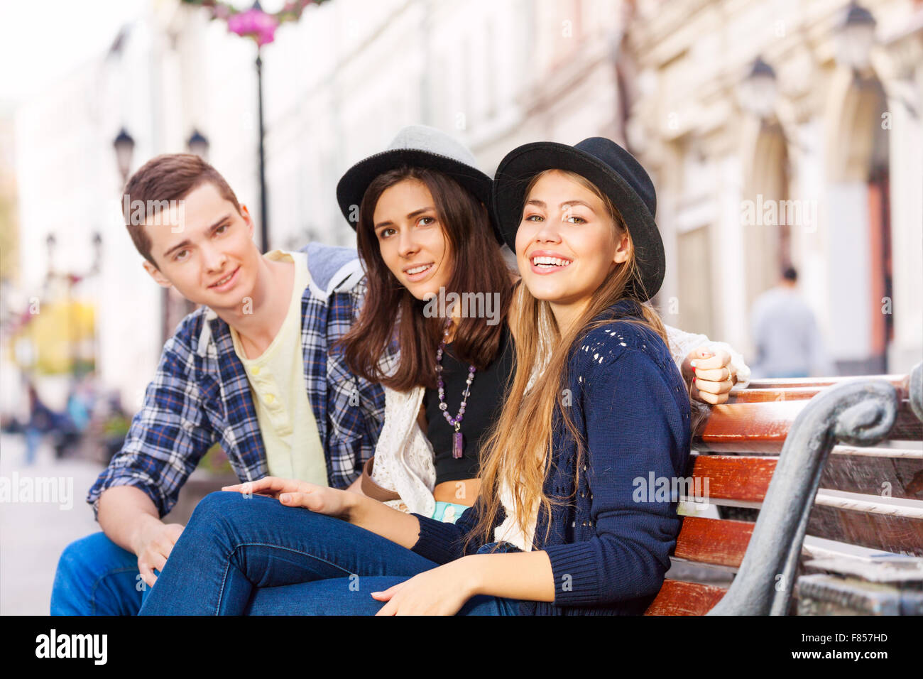 Three friends sitting together on the bench Stock Photo - Alamy