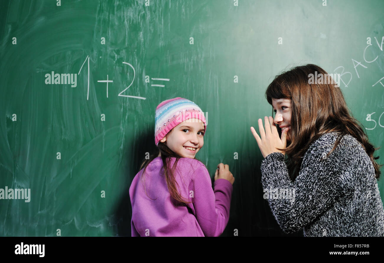happy child in school classrom solving math problem and have friend to ...