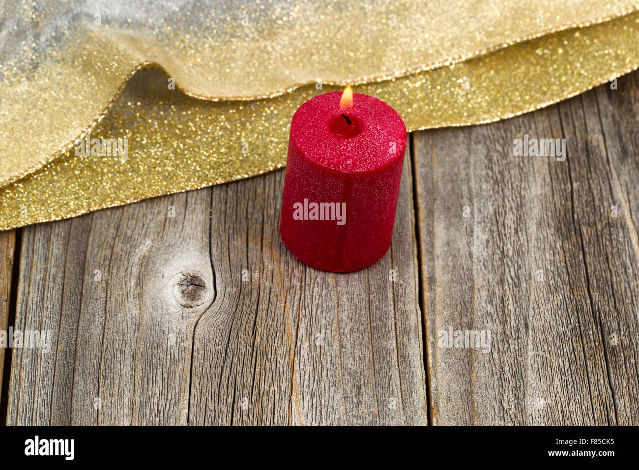 Close up of burning red candle with golden ribbon on rustic wood Stock ...