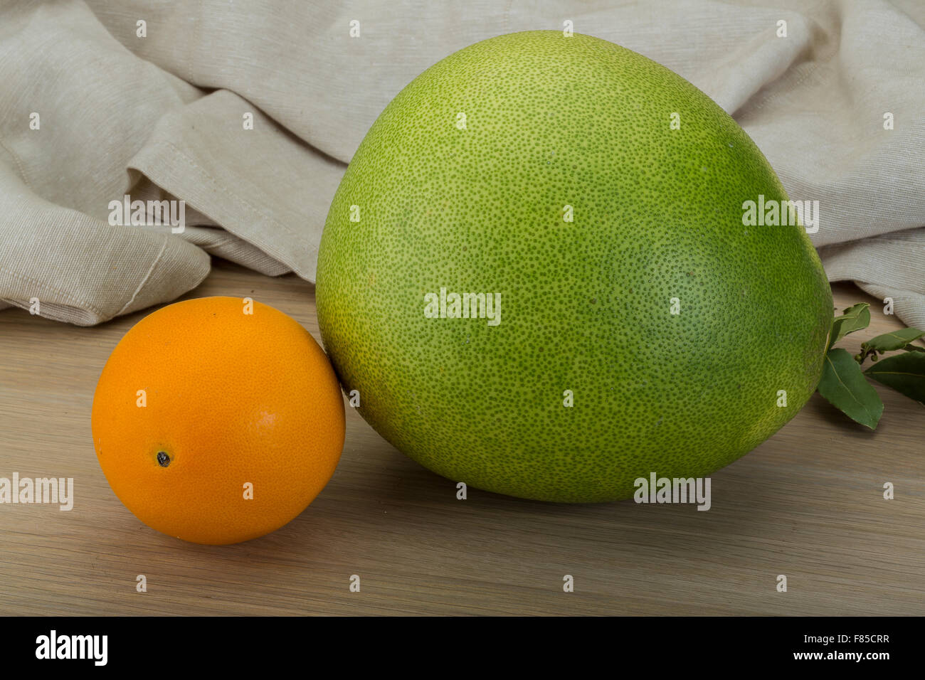 Green pomelo and orange on the wood background Stock Photo - Alamy