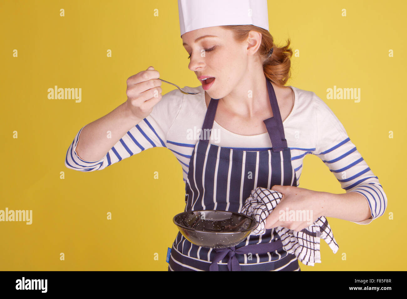 Portrait of an attractive female chef over a yellow background ...