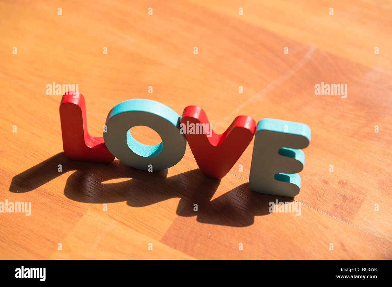 Wooden word LOVE lay on laminate floor in shadow shade style 3 Stock ...