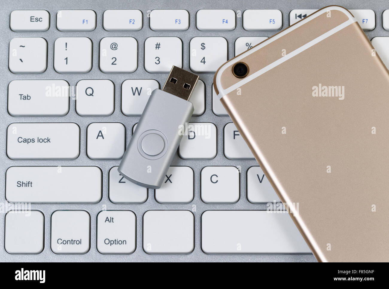 Close up view of cell phone, thumb drive and computer keyboard. Modern ...