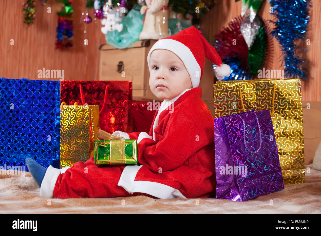 Boy dressed like Santa Claus with Christmas gifts at home Stock Photo ...