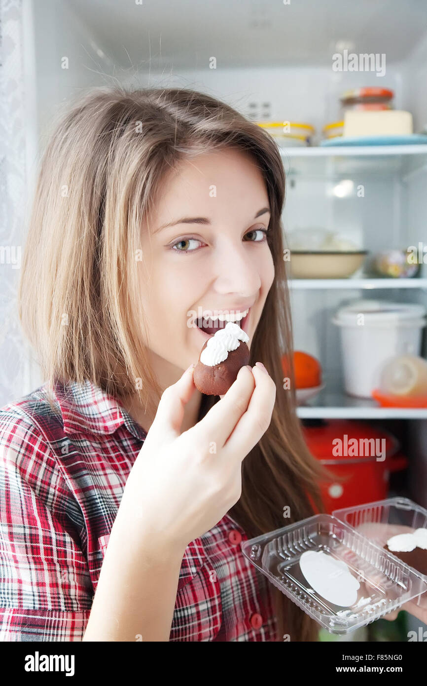 Teenager girl eating pastry from fridge at home Stock Photo - Alamy