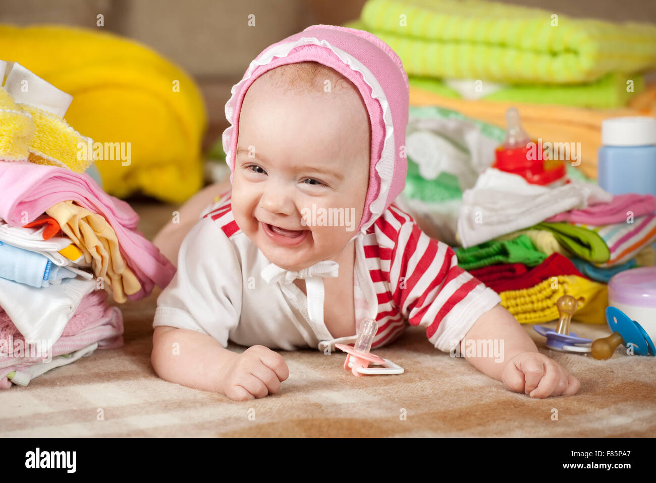 baby girl with stacked of children's clothes Stock Photo - Alamy