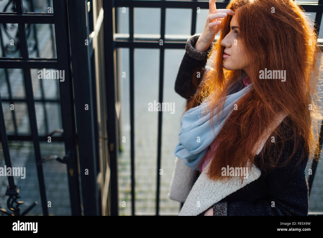 Red-haired girl standing on the street and laugh. Winter time, snow ...