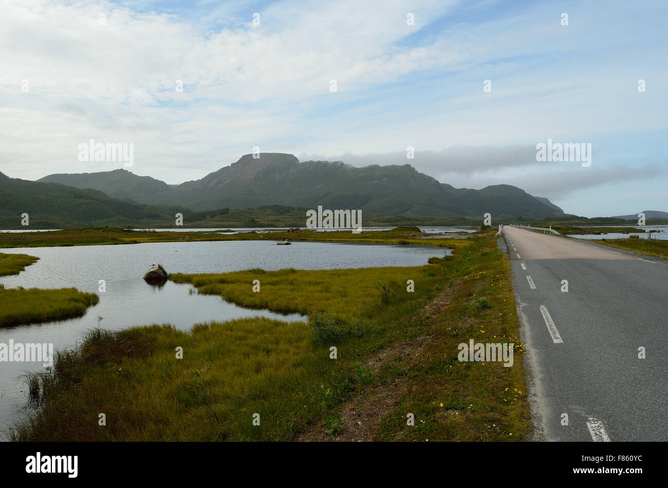 long strait road with ocean water on sides and mighty mountains in ...