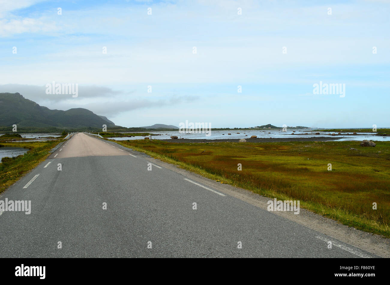 long strait road with ocean water on sides and mighty mountains in ...