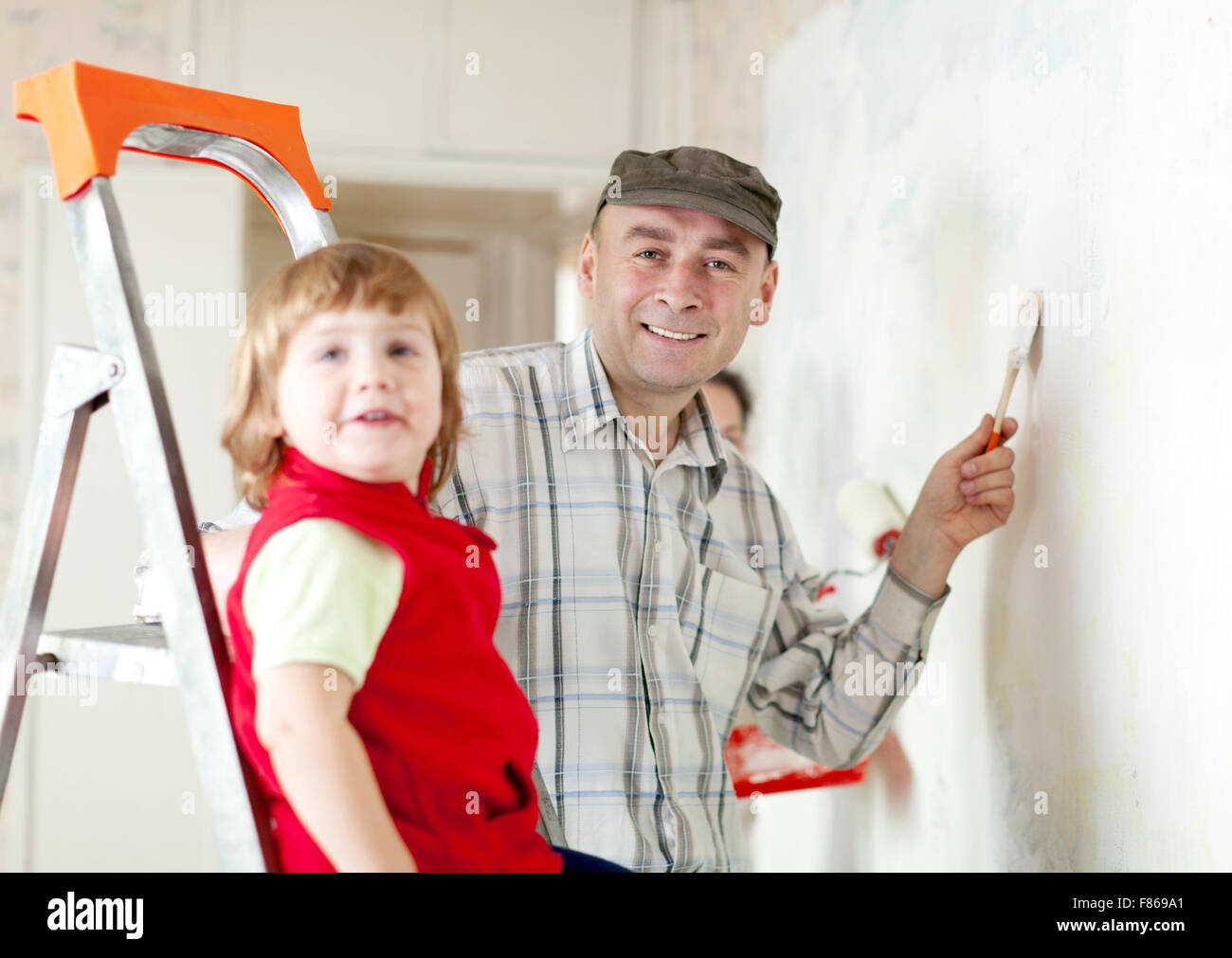 Parents with child paints wall at home Stock Photo - Alamy
