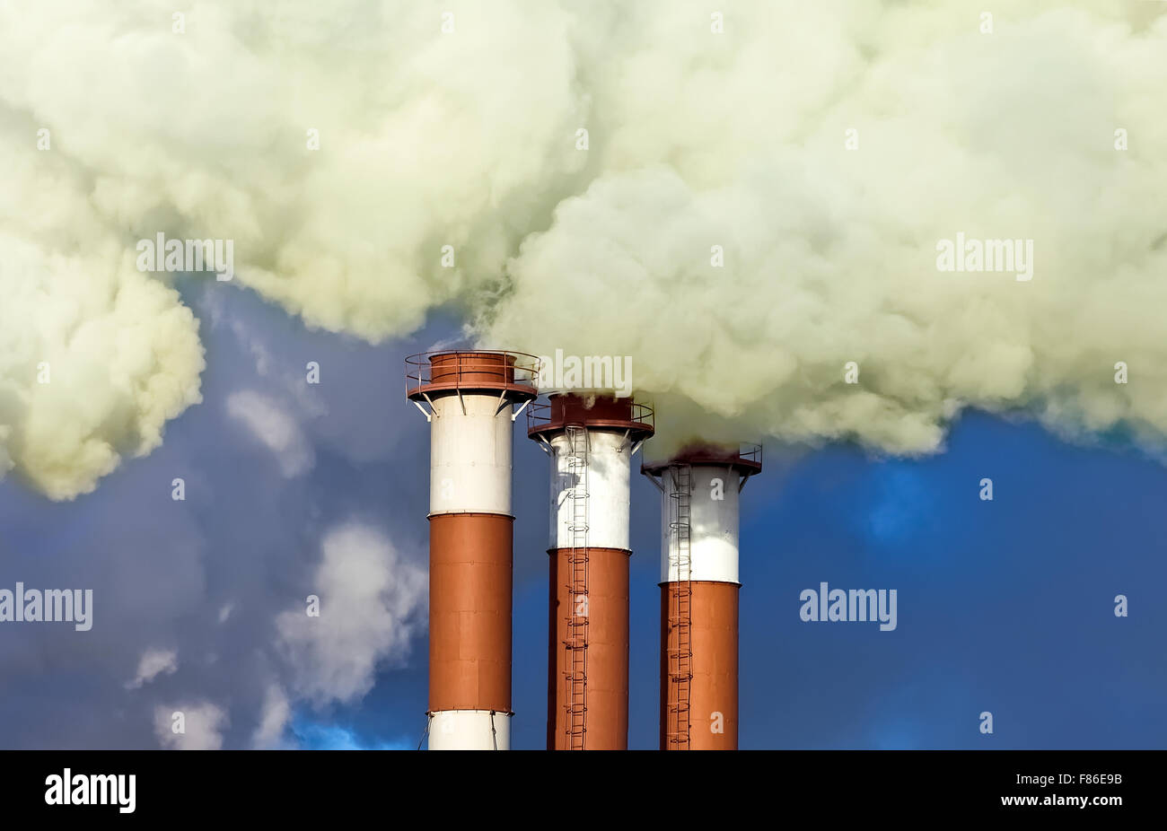 Industrial chimneys with smoke over blue sky Stock Photo - Alamy