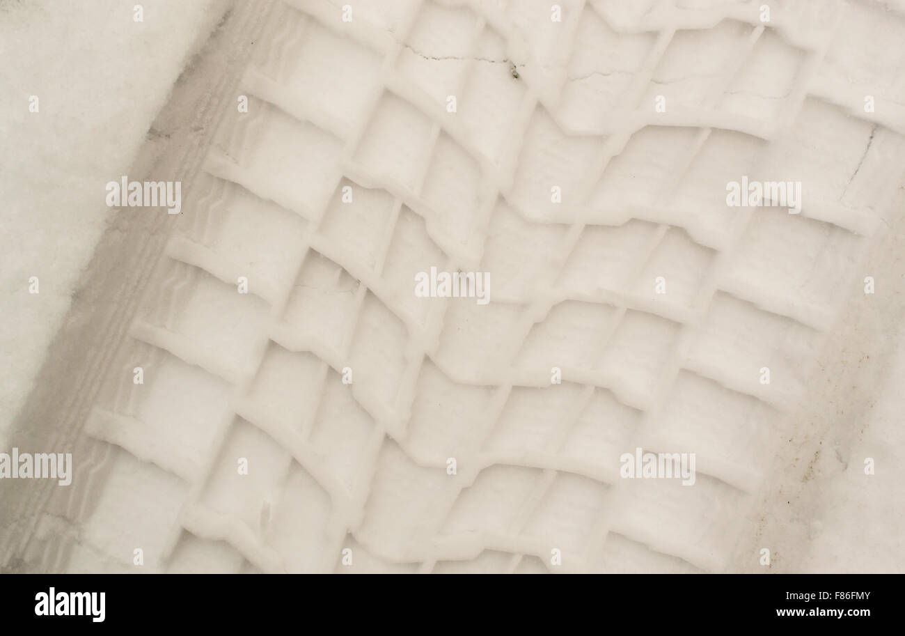 Car tire imprints dug into fresh winter snow during a snowstorm in the ...