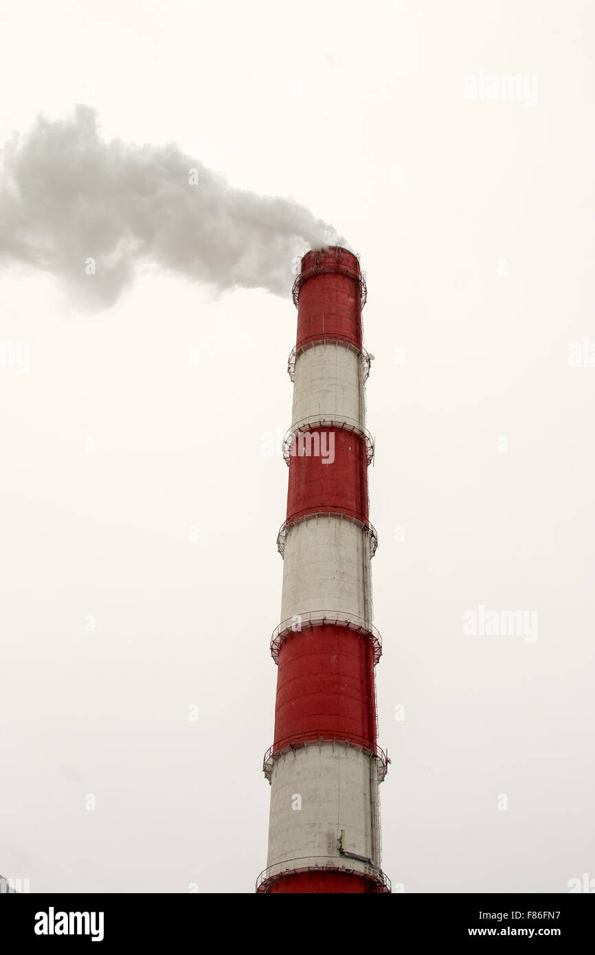 Red and white colored large towering industrial chimney emits smoke ...